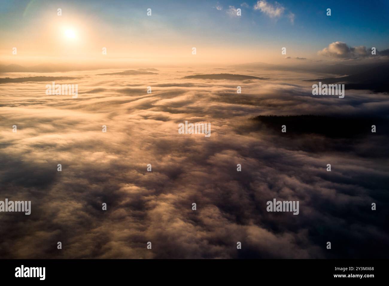 Aerial view of vibrant sunset over white dense clouds bathes in warm ...