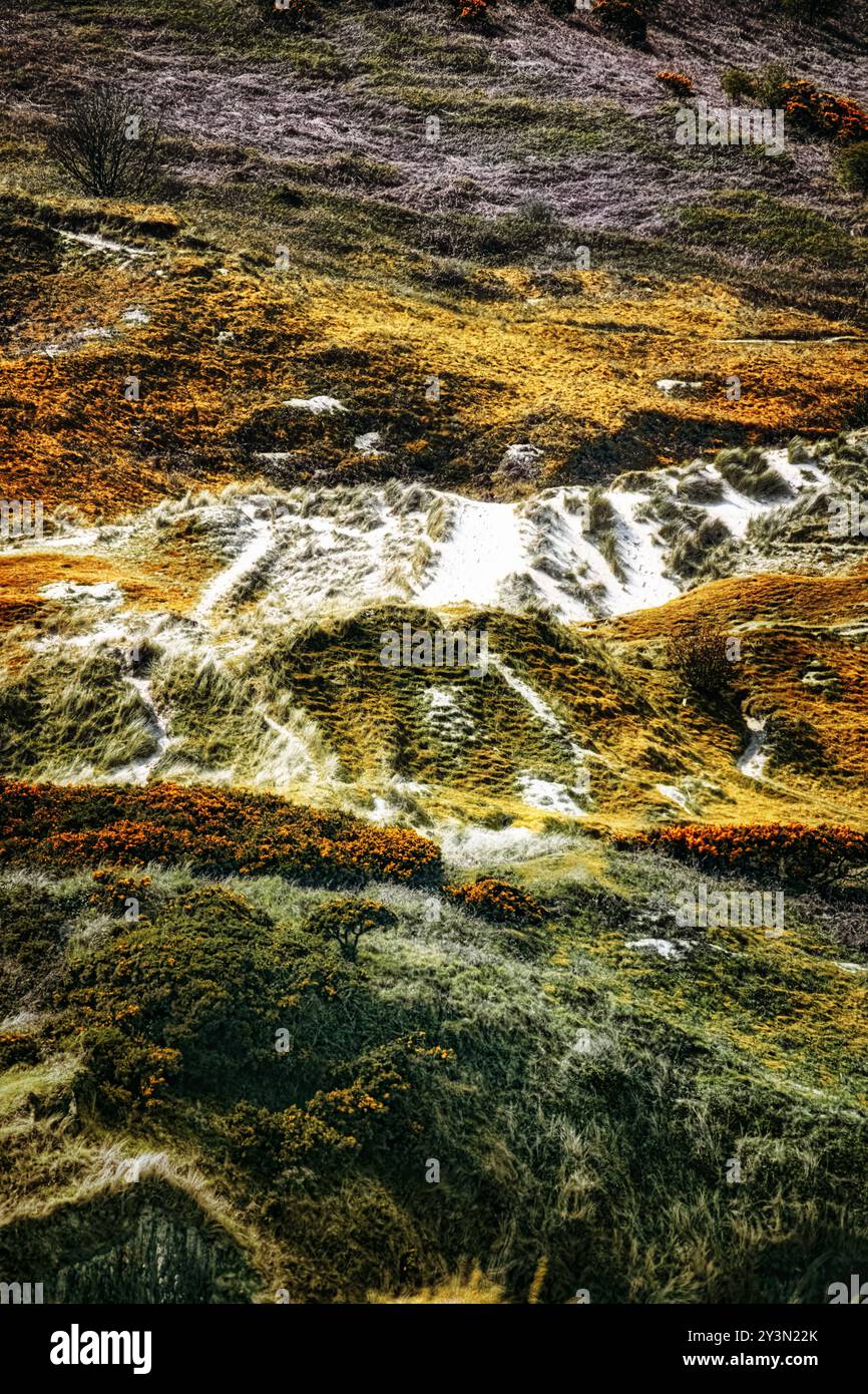 A coastal scene with a grassy cliff with patches of white sand Stock ...