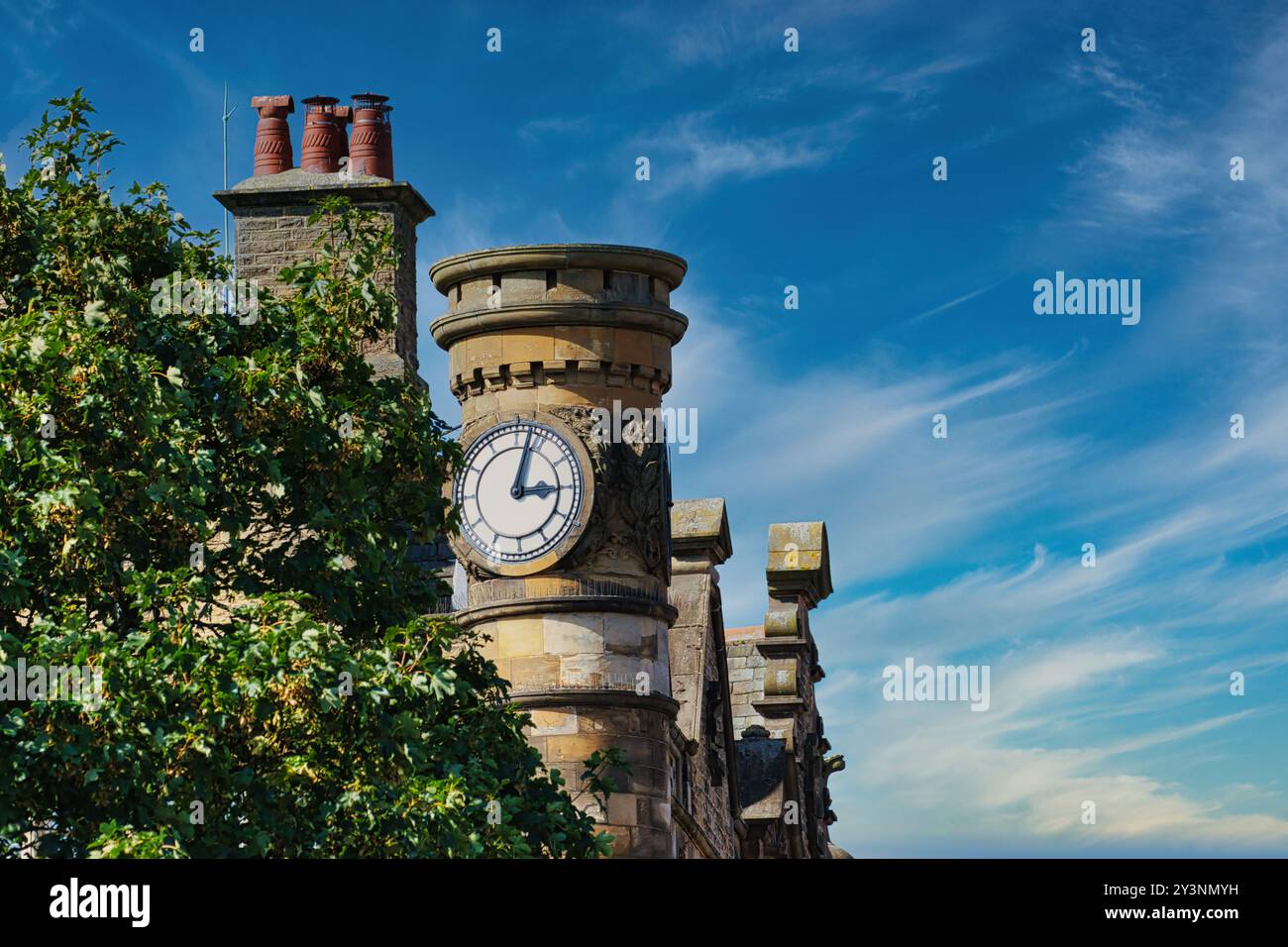 A historic clock tower with a large clock face, surrounded by lush ...