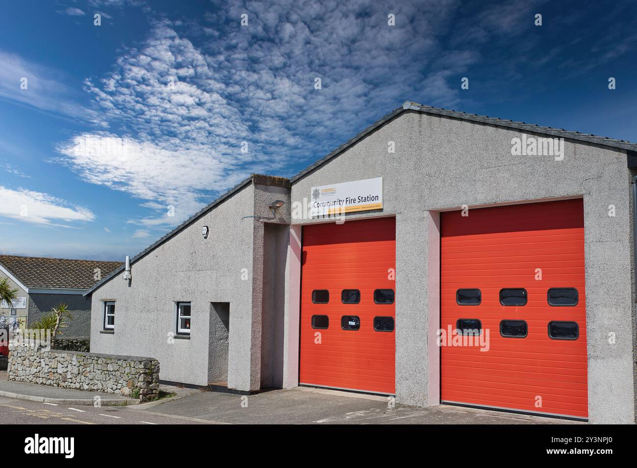 A community fire station with a gray exterior and bright orange garage ...