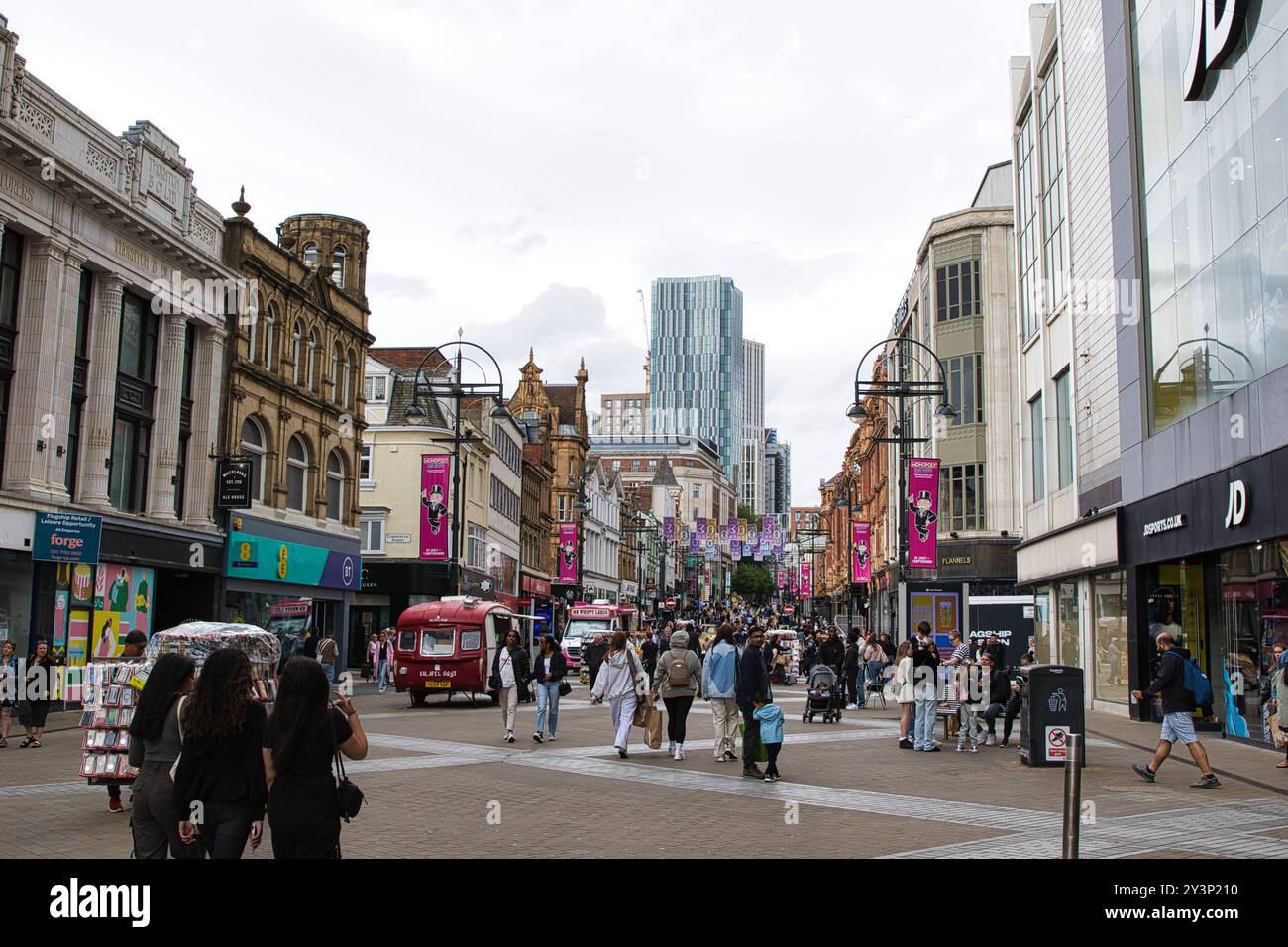 A bustling city street filled with pedestrians, shops, and colorful ...