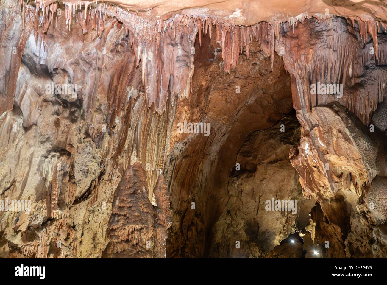 A cave with brown walls and a ceiling covered in ice. The cave is dark ...