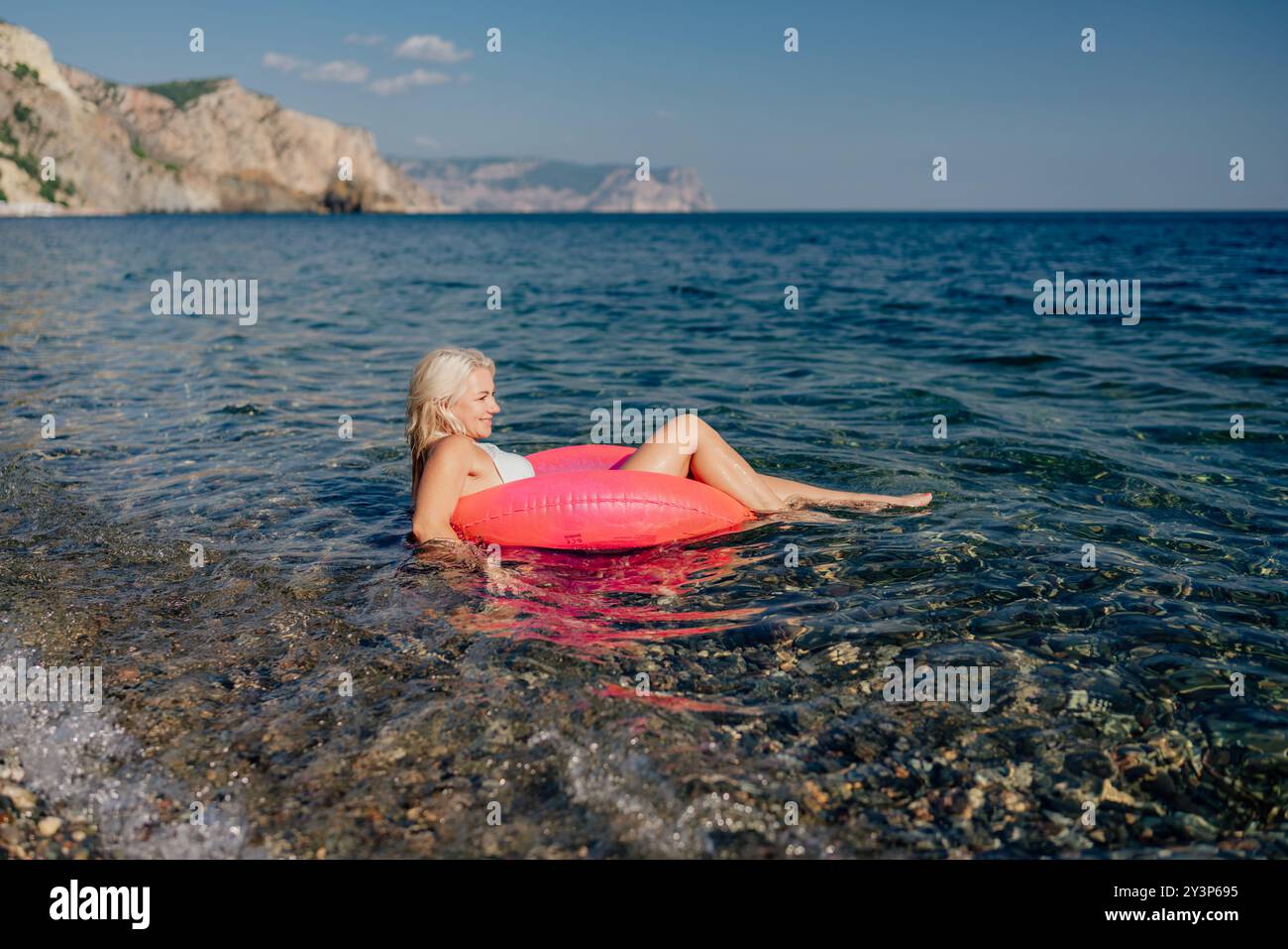 A woman is floating in a red inflatable tube in the ocean Stock Photo ...