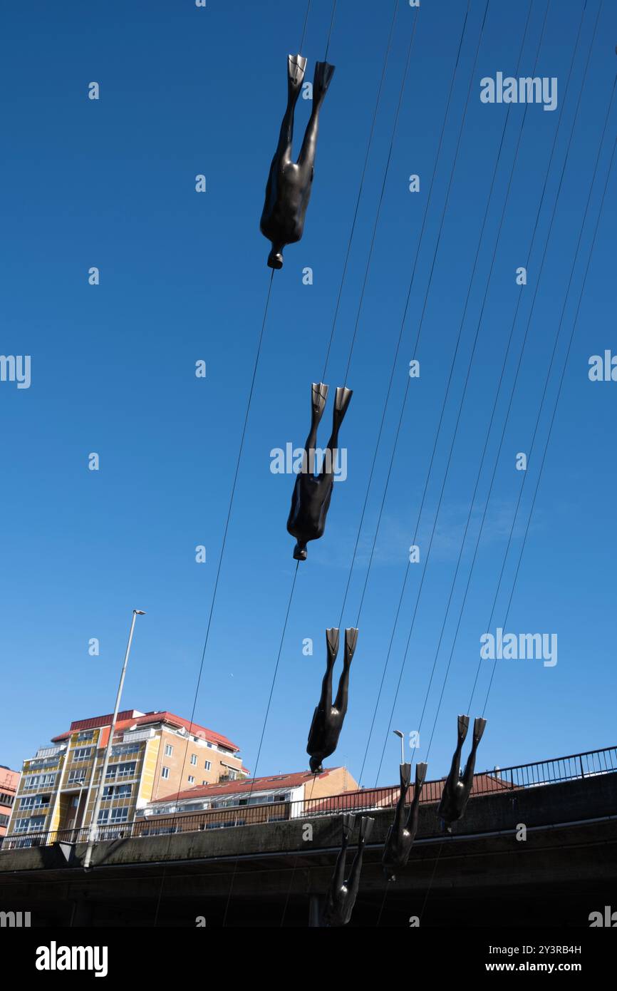 Statues of figures suspended on wire over the river river Akerselva ...