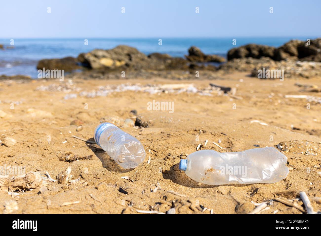 plastic bottles lie on a dirty sandy beach, ocean and coastline ...
