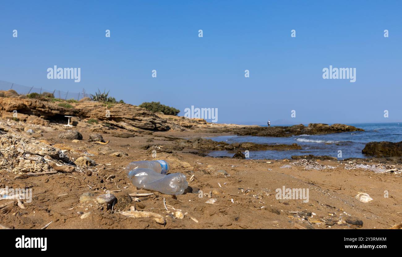 plastic bottles lie on a dirty sandy beach, ocean and coastline ...