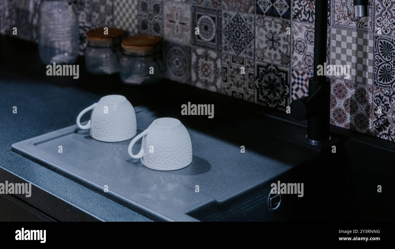 Two white upside down cups drying next to a sink in modern clean ...
