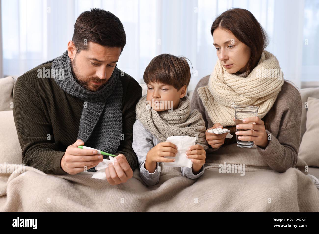 Cold symptom. Family suffering from fever on sofa at home Stock Photo ...