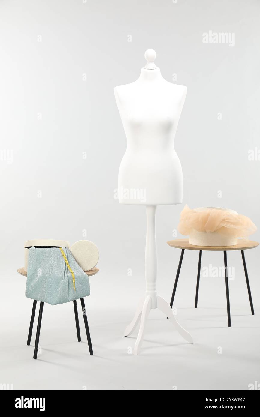 Mannequin with fabric and boxes on side tables against light grey ...