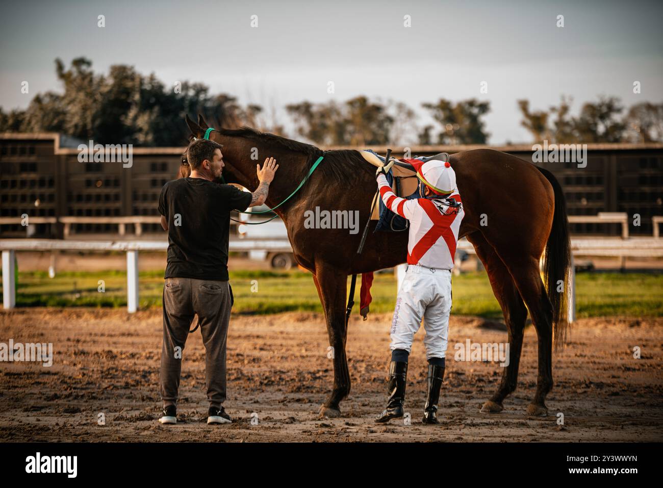 A jockey prepares his horse alongside a team member at the Palermo ...
