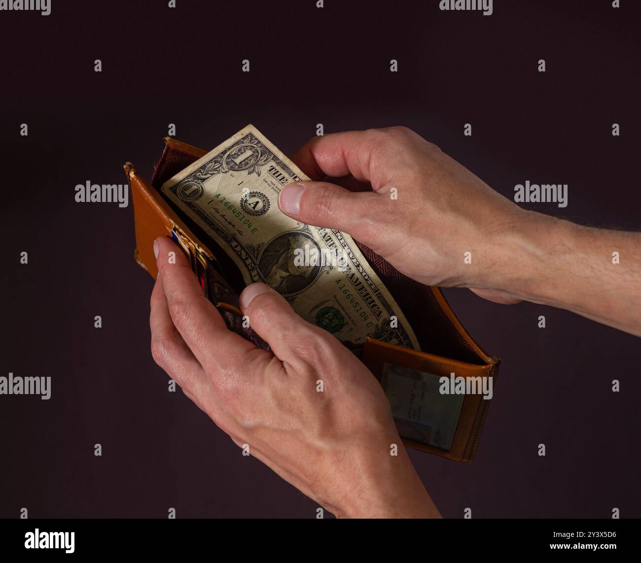 A man's hands hold open an old wallet with only one dollar left Stock Photo - Alamy