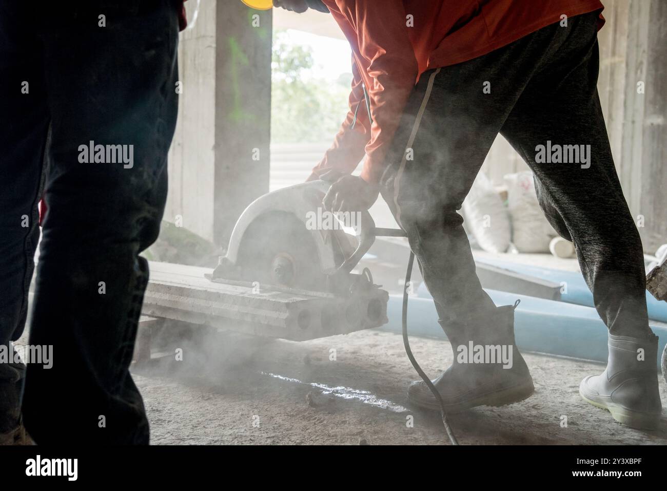 A builder using a circular saw to cut a large concrete piece Stock ...