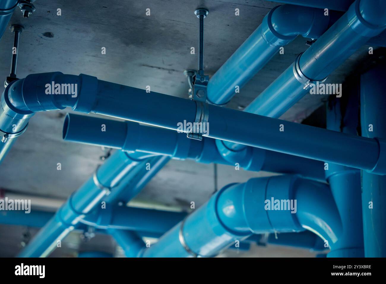 A bright blue pipes attached to a solid concrete wall Stock Photo - Alamy