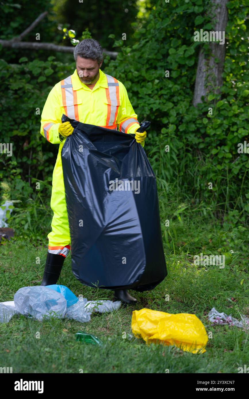Man cleaning up the park, putting trash in a garbage bag. Environmental ...