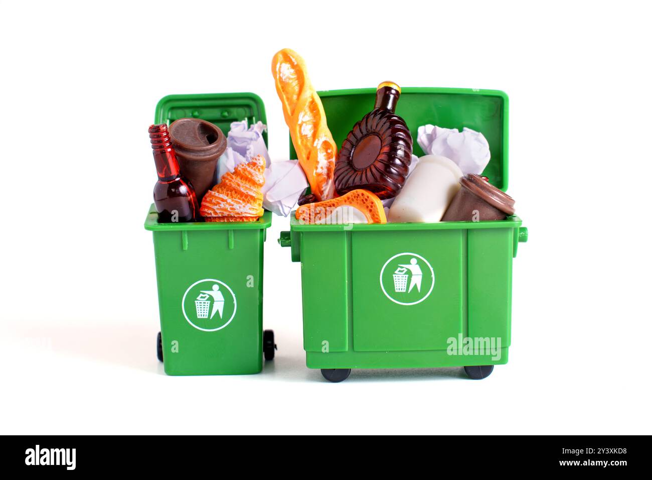 Miniature green recycling bins overflowing with various trash items on ...