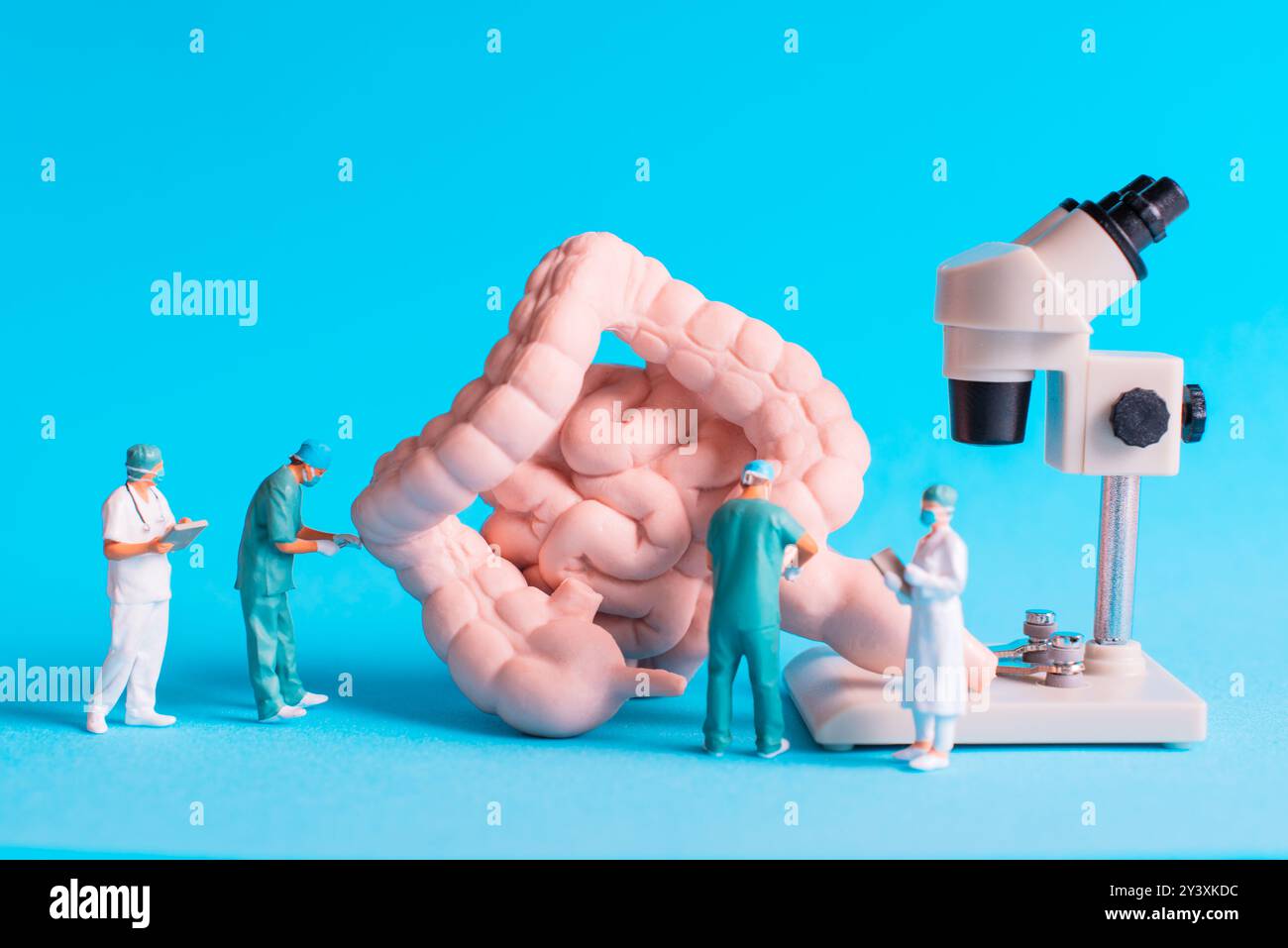 Miniature figures of medical professionals inspecting a model of the ...