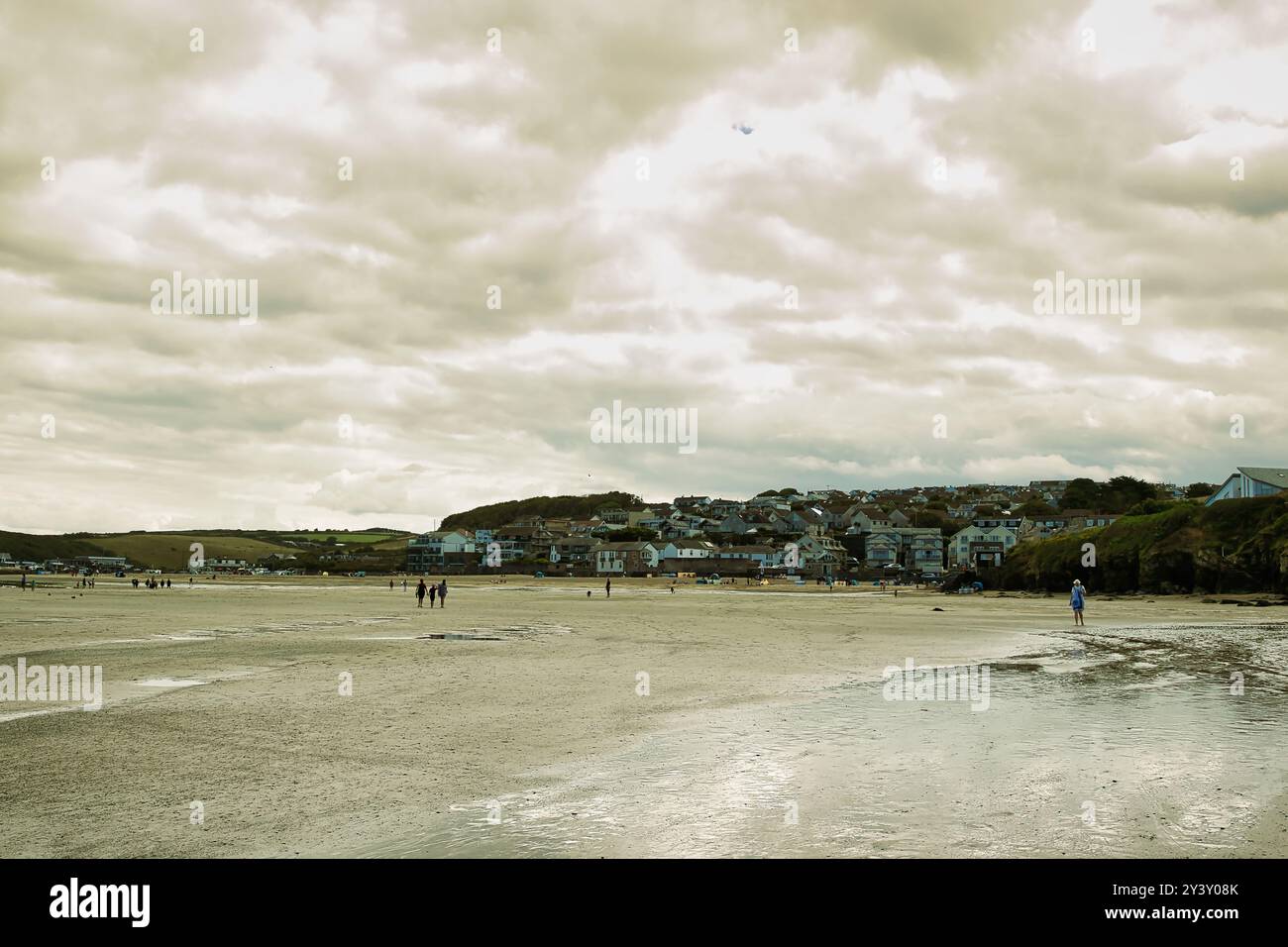 A serene beach scene with a wide sandy shore, low tide revealing wet ...