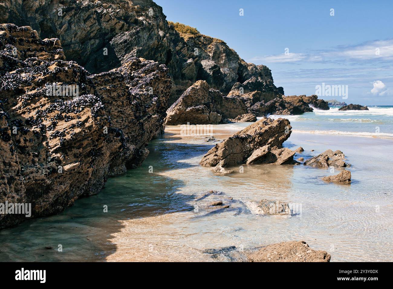 A serene beach scene featuring rugged rocks and clear water. The ...