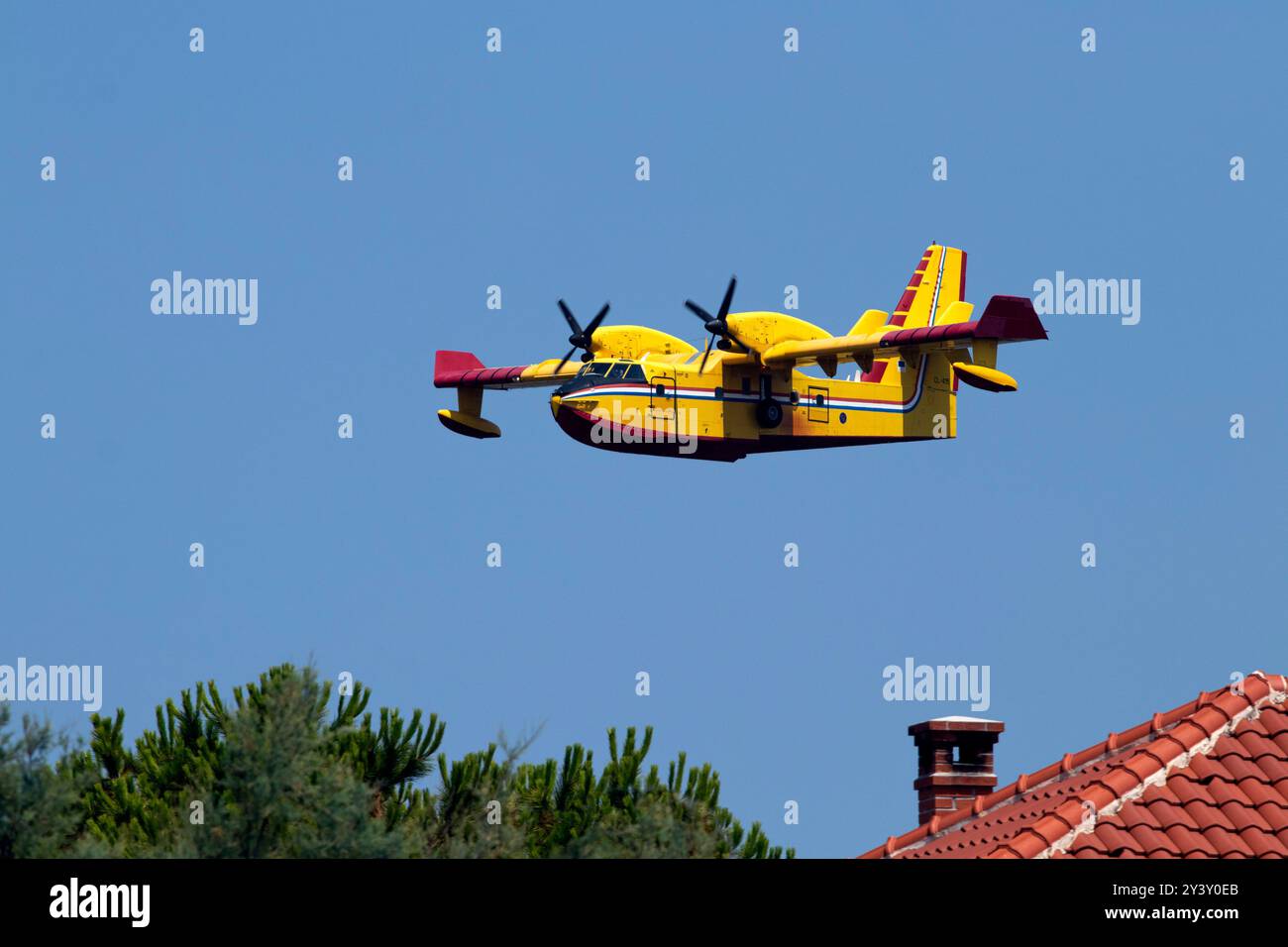 Yellow firefighting airplane flying low over residential area with a ...