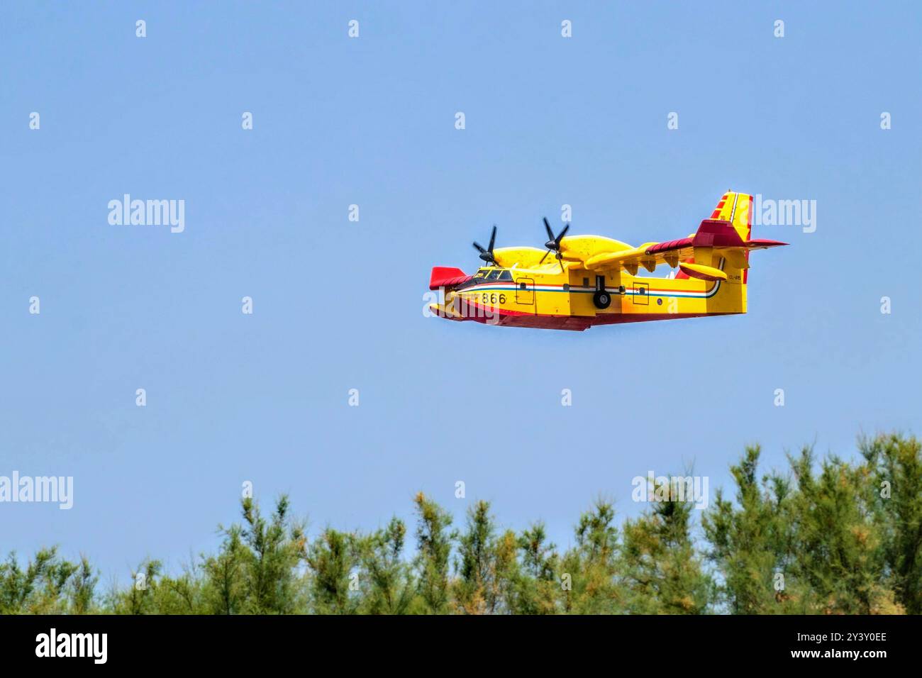 Yellow firefighting airplane flying low over residential area with a ...