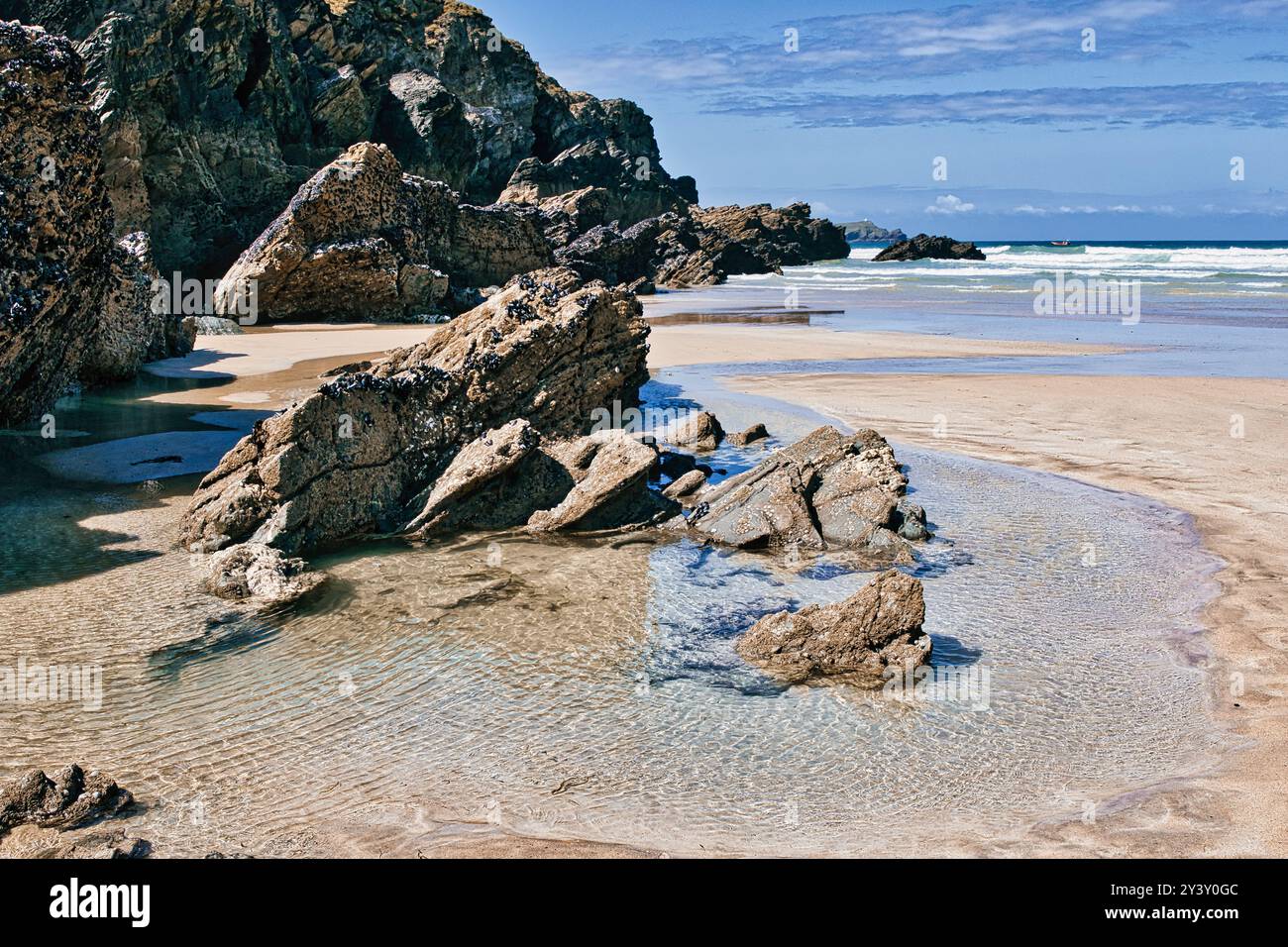 A serene beach scene featuring large rocky formations along the shore ...