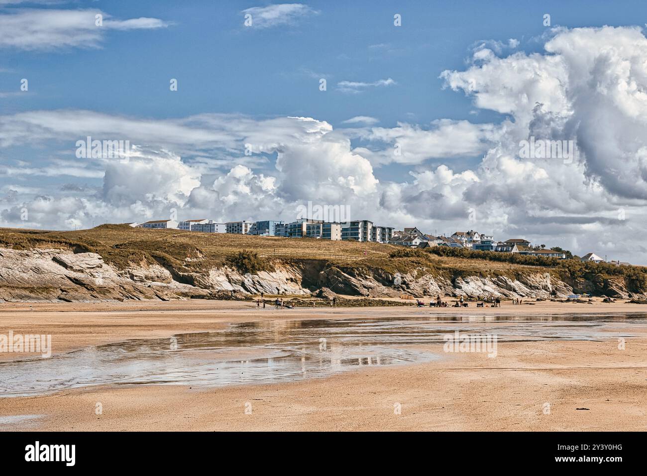 A scenic beach view featuring a sandy shore with gentle waves, rocky ...