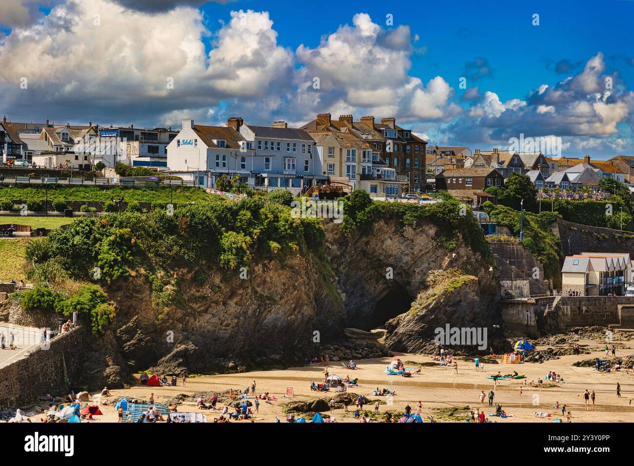A scenic beach view featuring a rocky cliff with houses on top ...