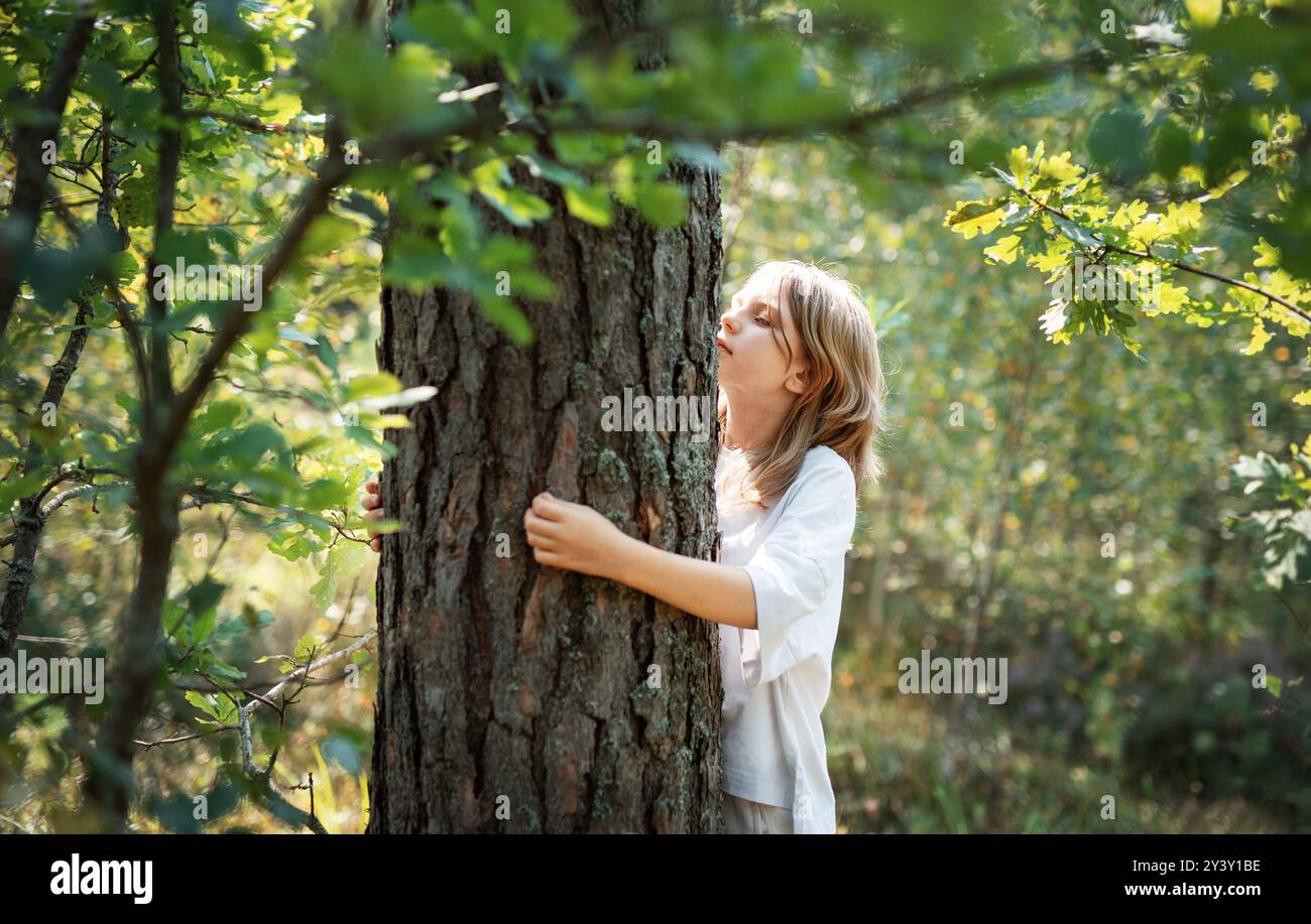 A teenage girl hugs a tree in the forest. Hugging and touching trees to ...