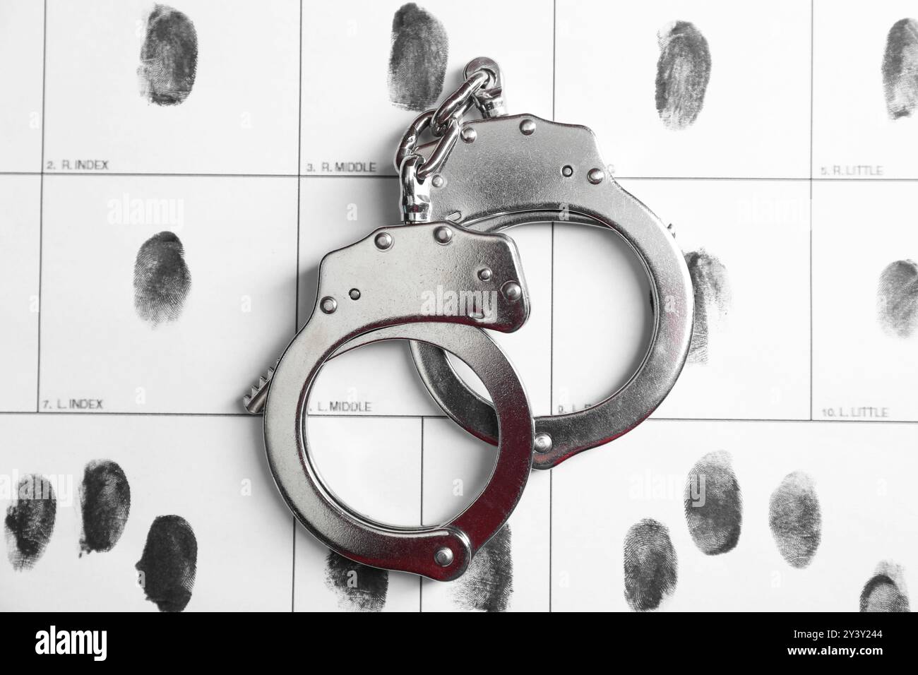 Human fingerprints and handcuffs on paper, top view. Criminal ...