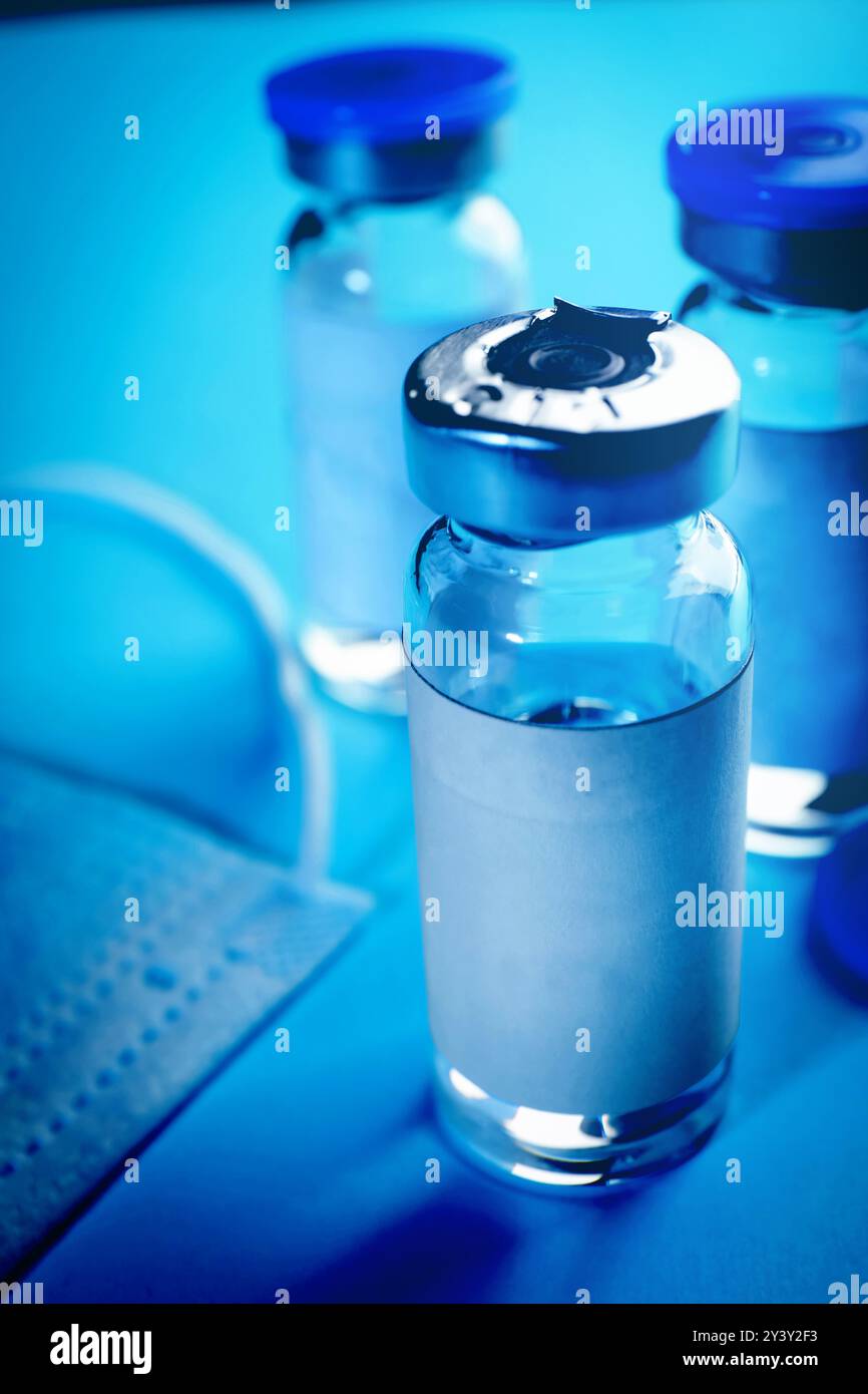 Medication in glass vials with blank labels on light blue background ...