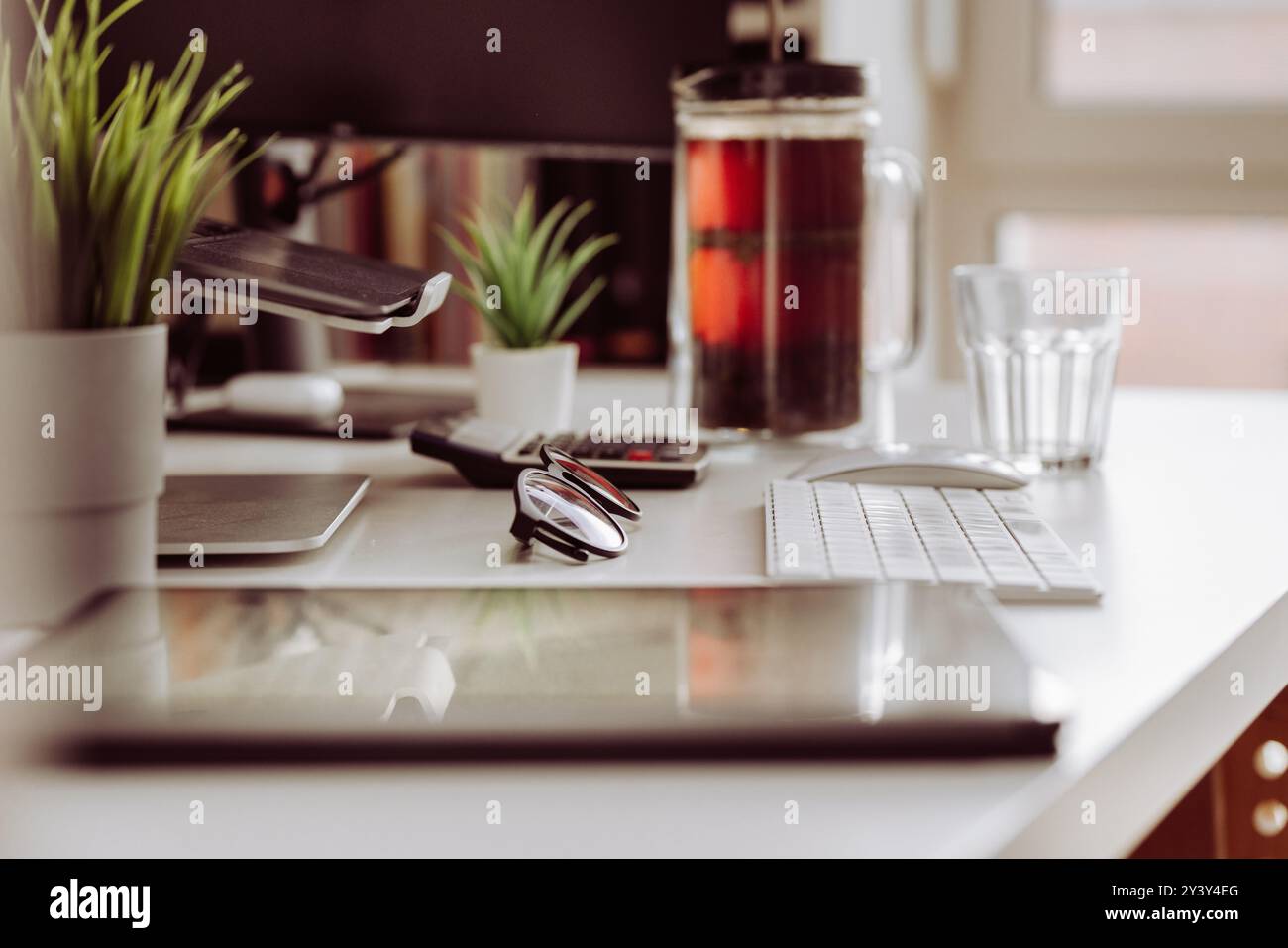 Cozy bright workplace. Home office equipment. White table green plants ...