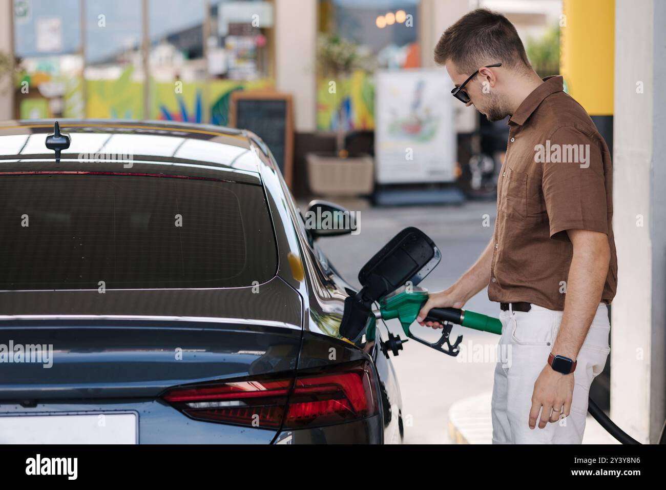 Handsome man start refueling car at self service gas station. Petrol ...