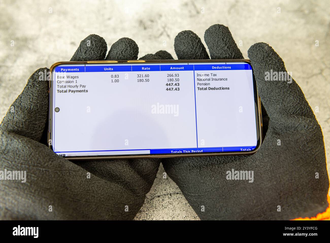 A worker wearing work gloves holding with both hands, a digital pay ...