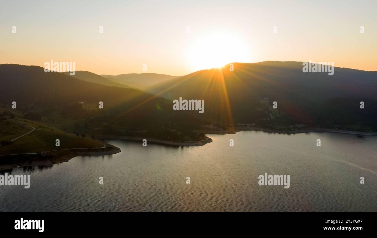 Lake and mountains surrounded by forests in the colorful rays of the ...