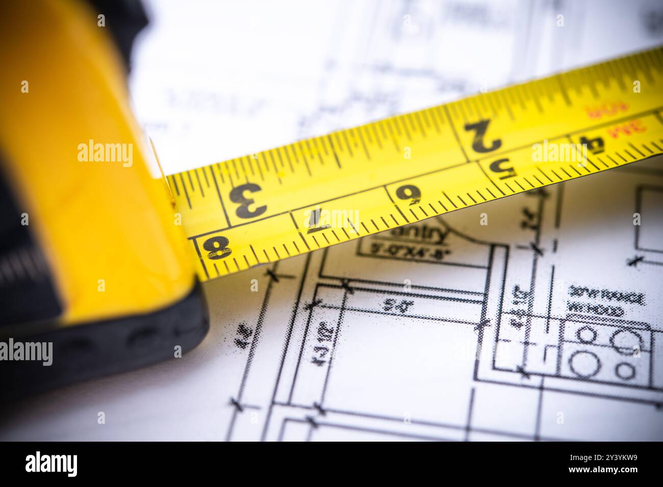 Yellow tape measure rests on detailed architectural blueprint ...