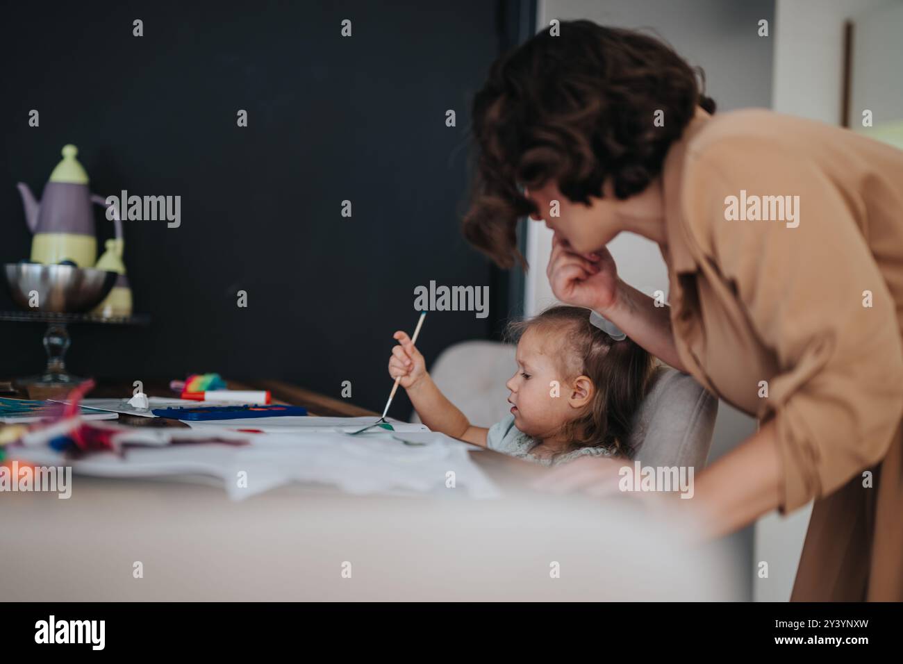 Mother guiding her daughter during a fun painting activity Stock Photo ...