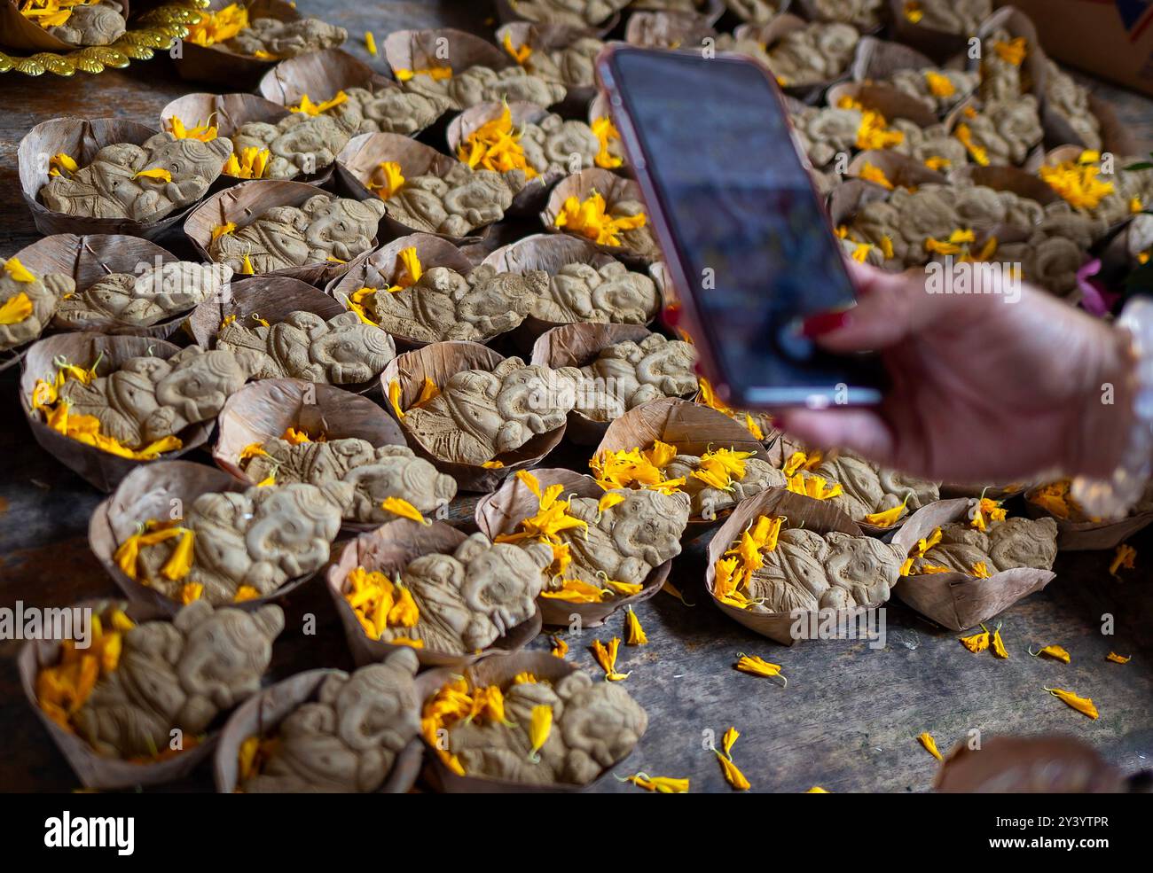 A devotee is photographing a small clay idol of Lord Ganesha that will ...