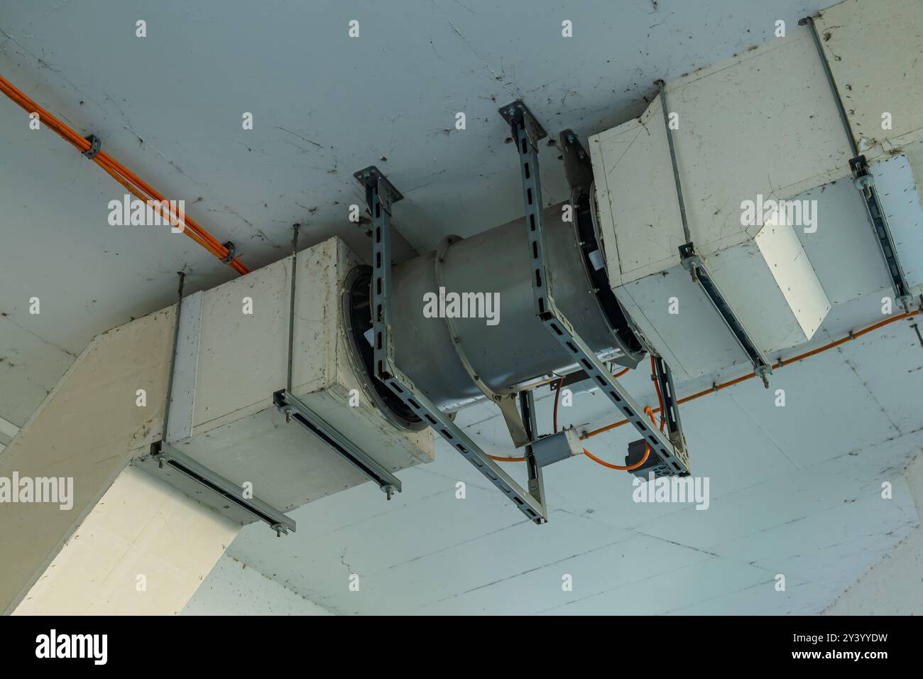 A complex network of industrial ductwork is installed on the ceiling of ...