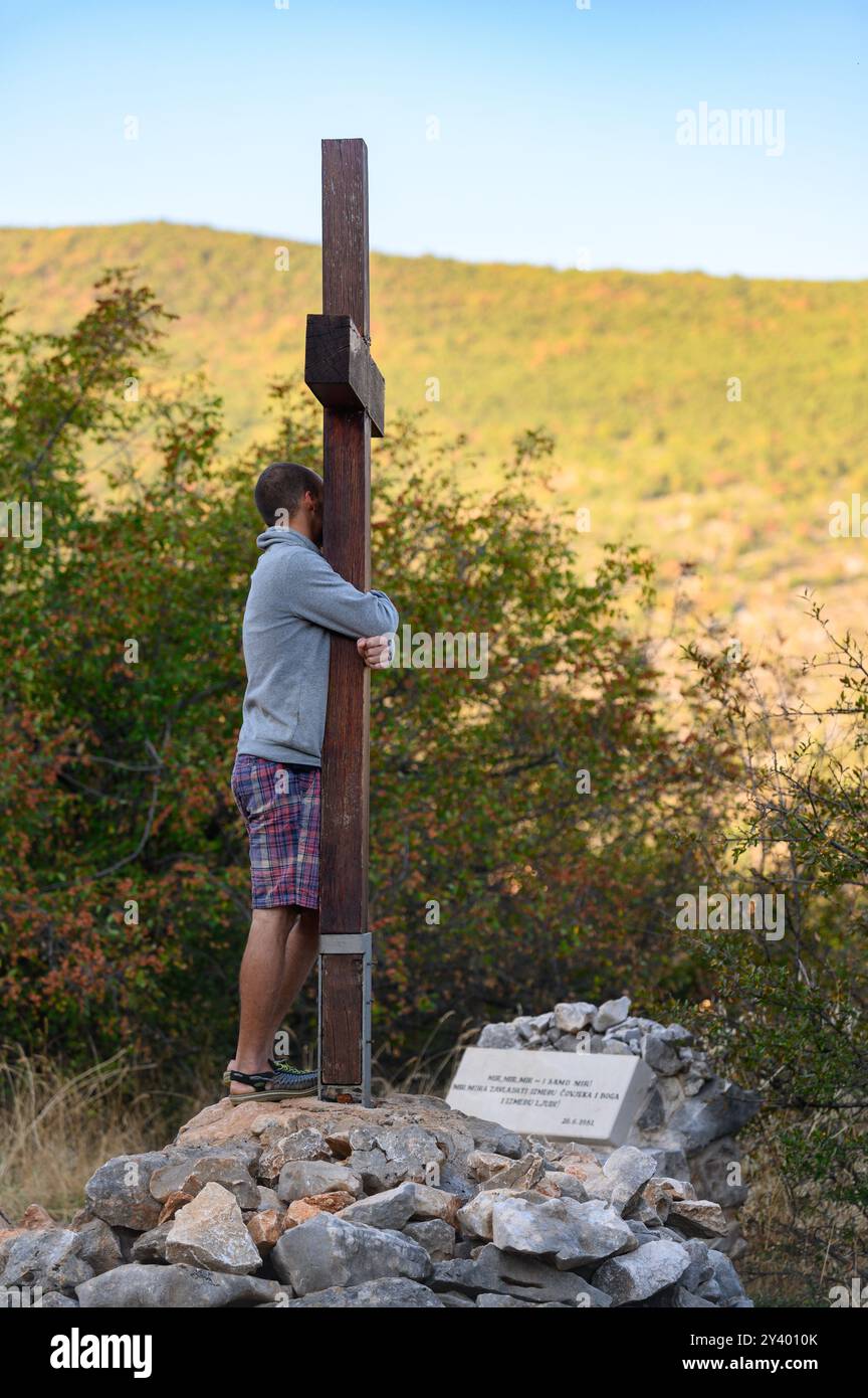 A young man embracing the cross on the spot on Mount Podbrdo in ...
