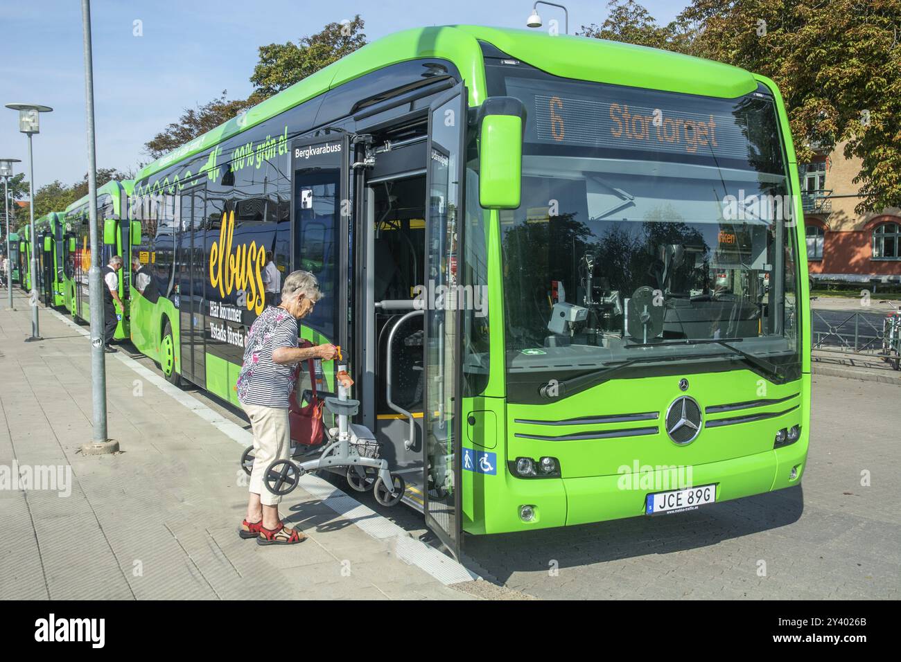 Elderly woman boards an electric bus in Ystad, Skane County, Sweden ...