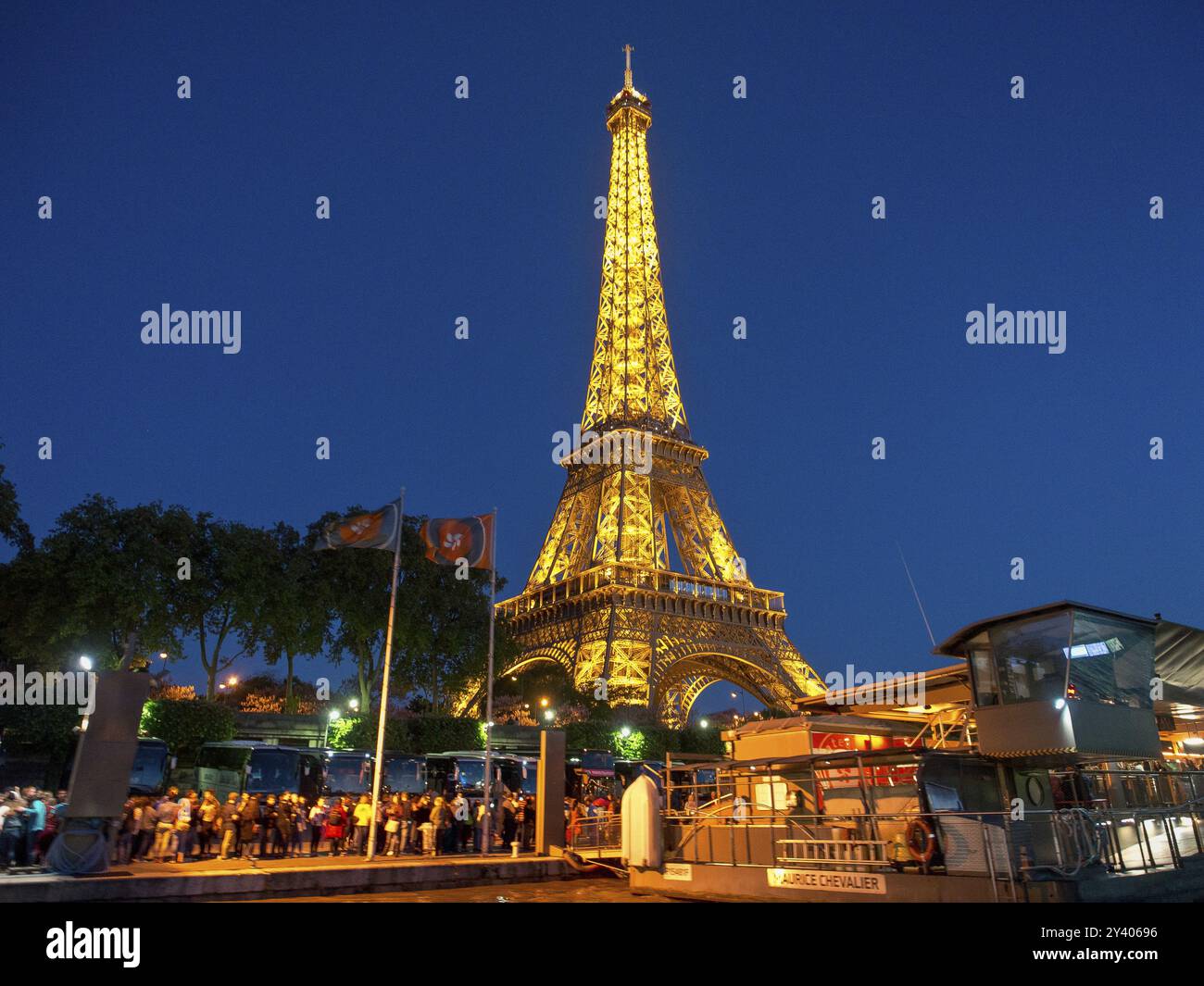 Shining Eiffel Tower at night, reflected in the Seine, people enjoying ...
