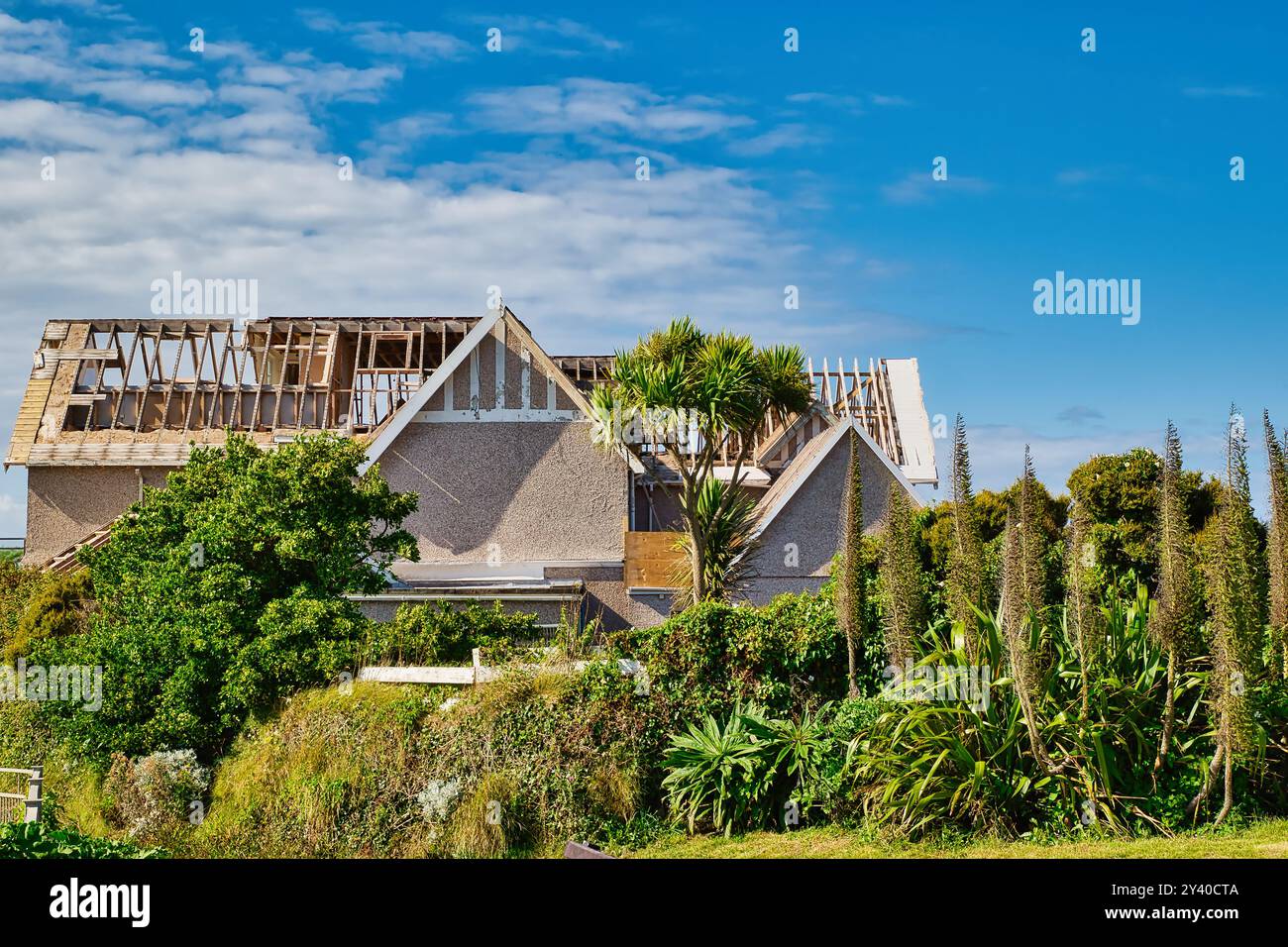 A partially constructed house with a visible roof frame, surrounded by ...