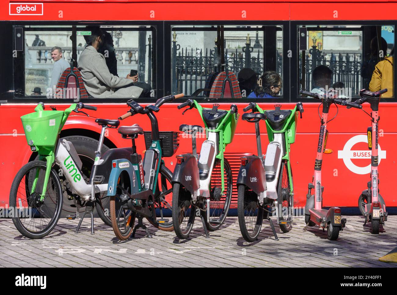 London, UK. Lime rental cycles parked as a red London bus goes past ...