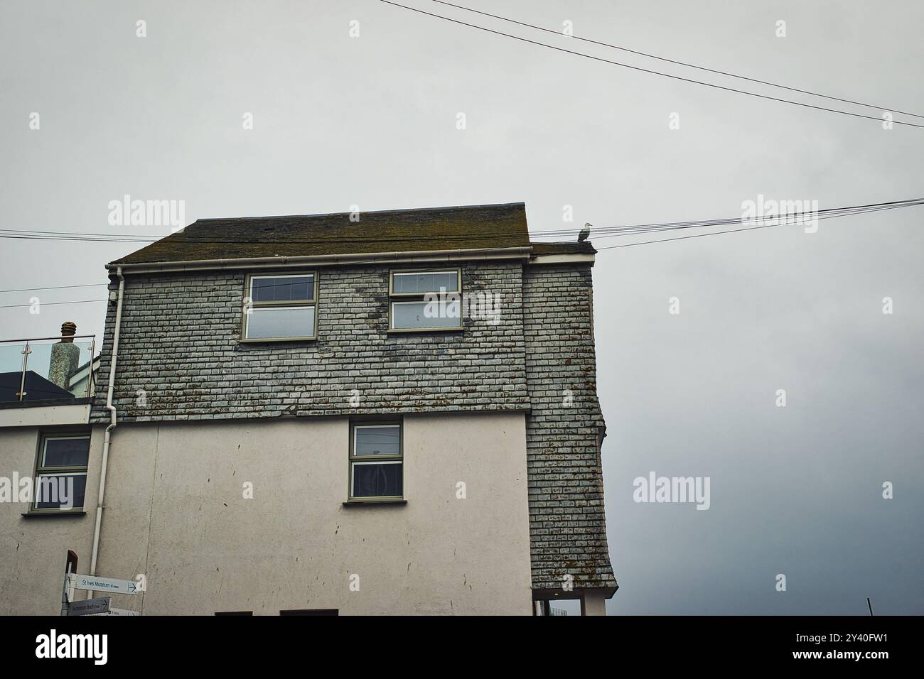 A weathered building with a sloped roof, featuring a mix of shingles ...