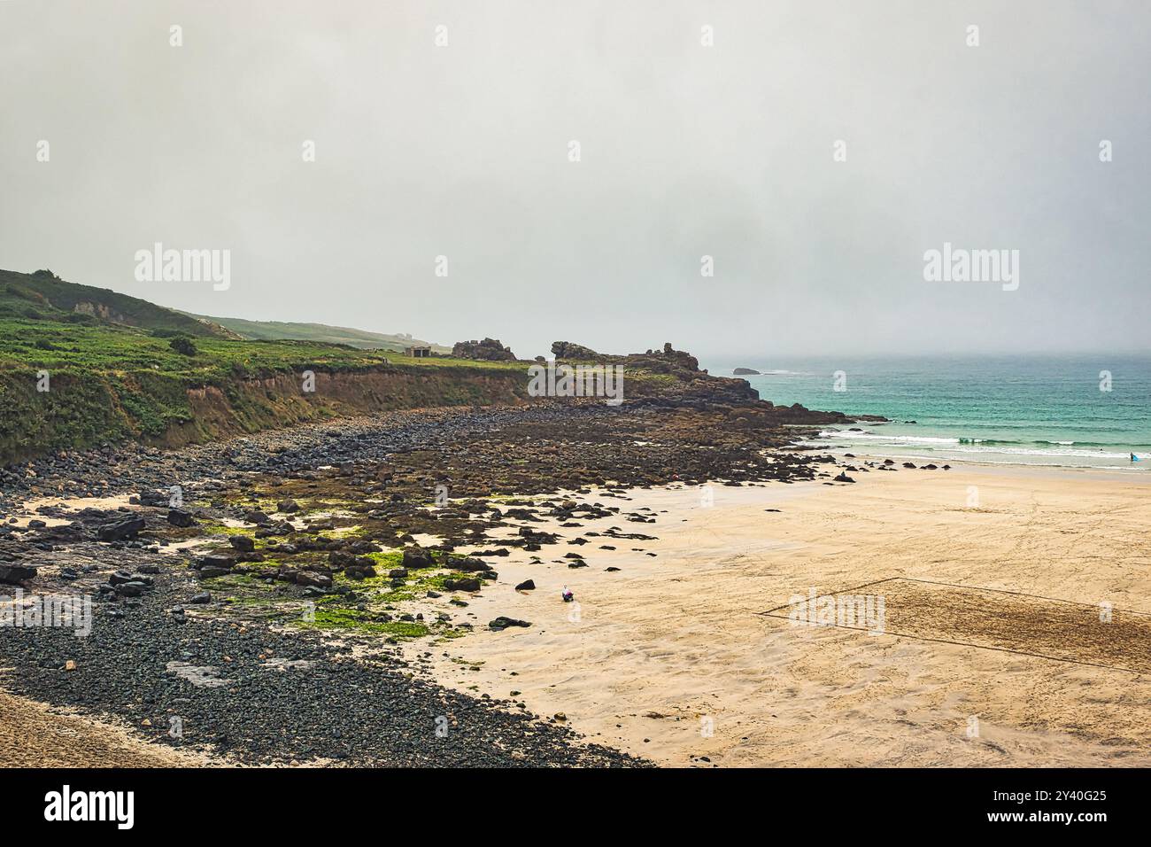 A serene beach scene featuring a rocky shoreline, gentle waves, and a ...