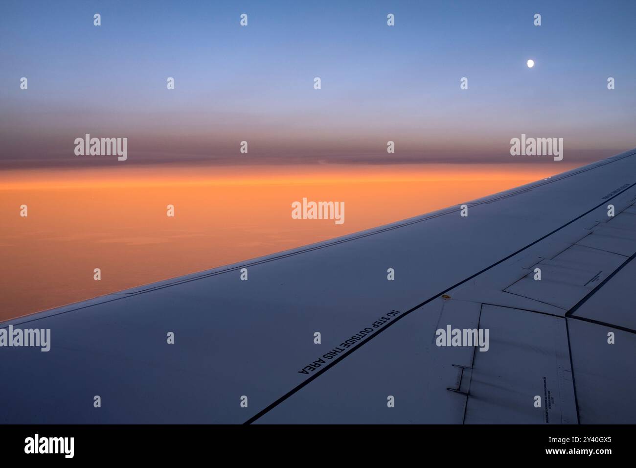 Airbus A220-300 flying above sea of clouds in sunset, the moon is ...