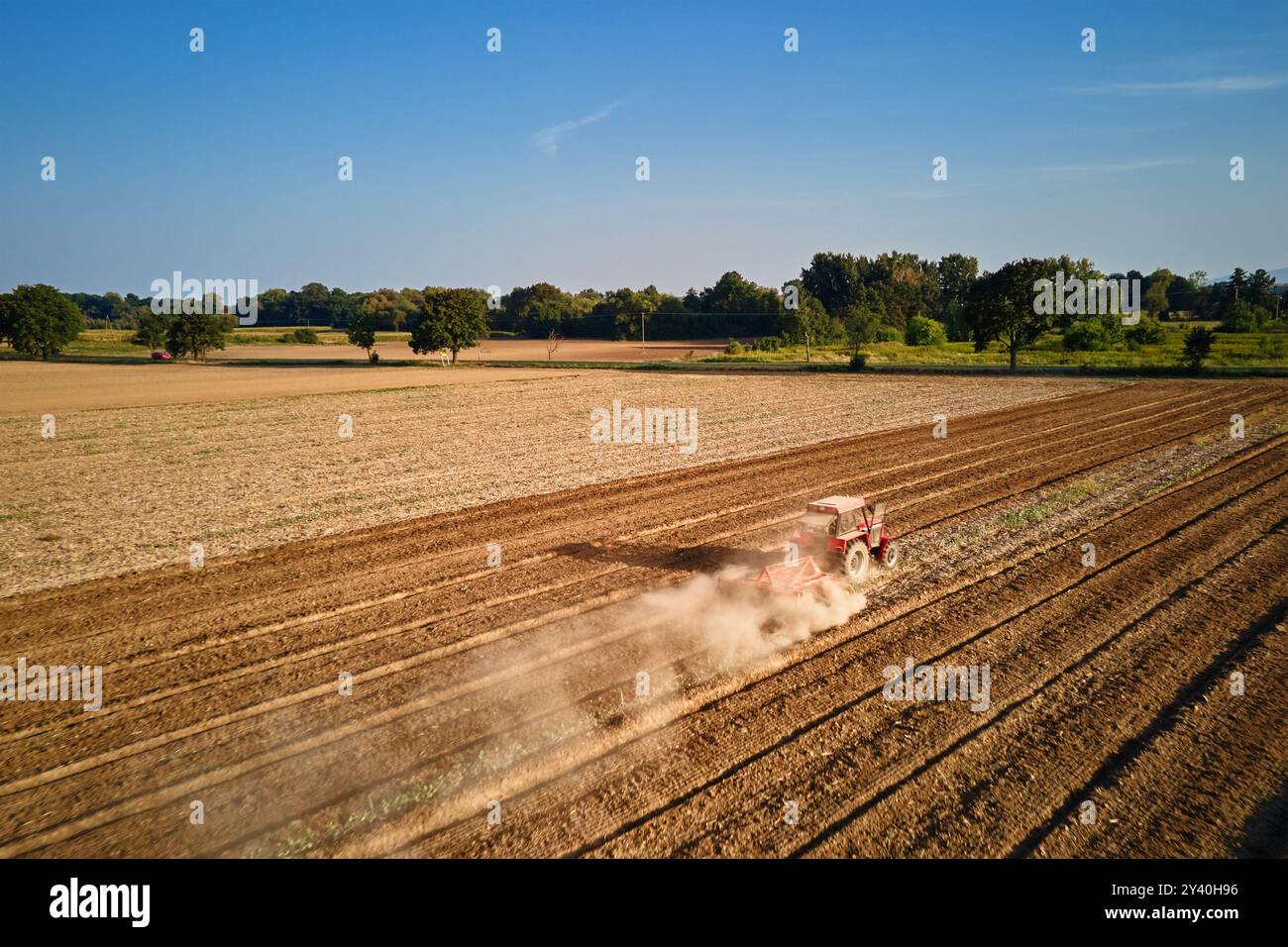 Red tractor working in agricultural field, cultivating and plowing dry ...