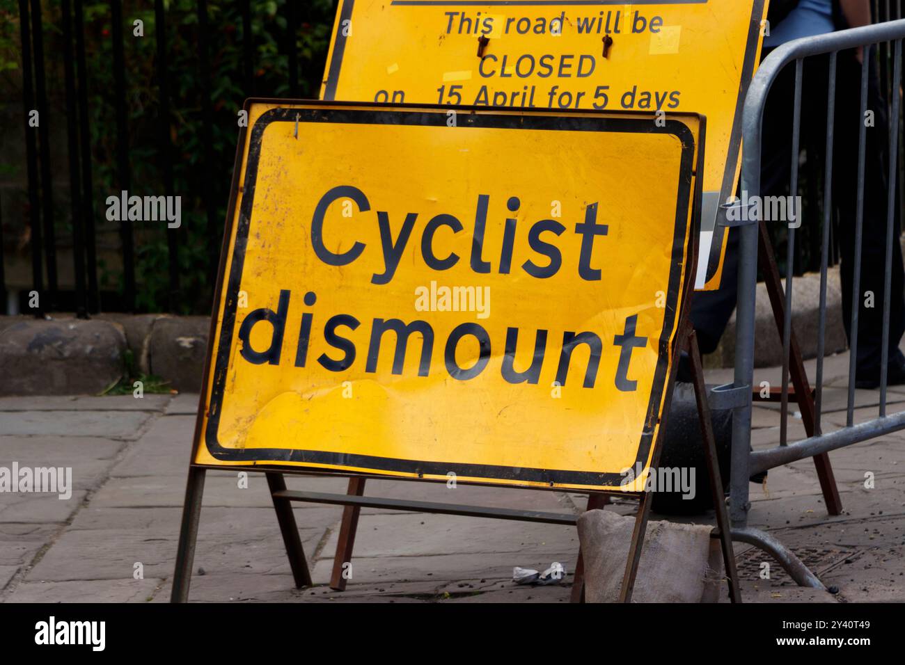 yellow warning sign instructing cyclists to dismount from their bike ...