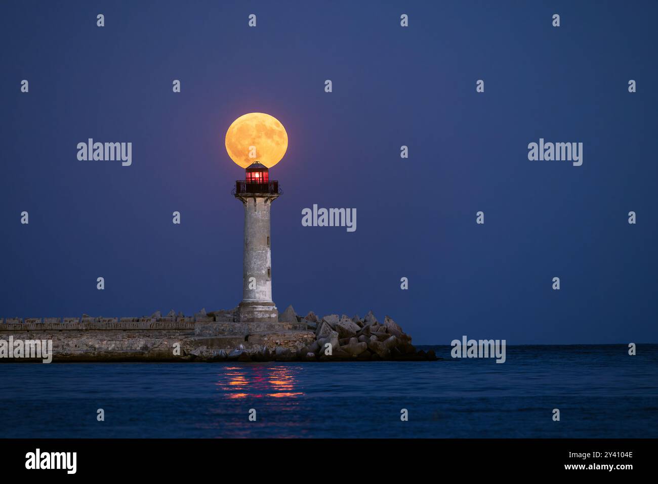 Lighthouse beacon and full moon twilight over sea horizon and moonlight ...