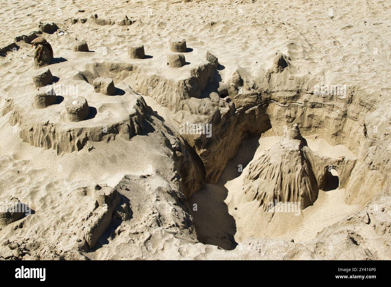 A detailed sandcastle with various towers and a moat, set on a sandy ...